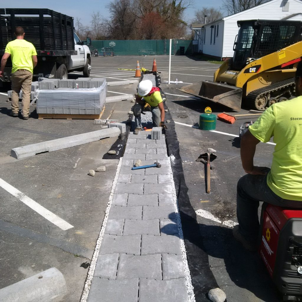 Contractors working to install permeable pavers over an infiltration ...